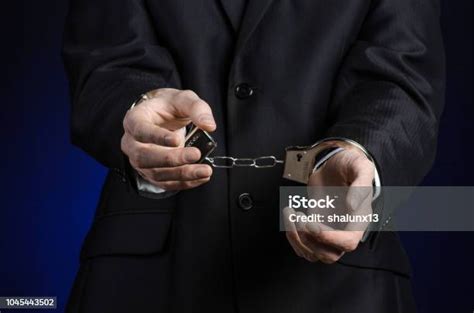 부패와 뇌물 테마 고립 된 스튜디오에 진한 파란색 배경에 그의 손에 수 갑과 검은 양복에 사업가 고소에 대한 스톡 사진 및 기타