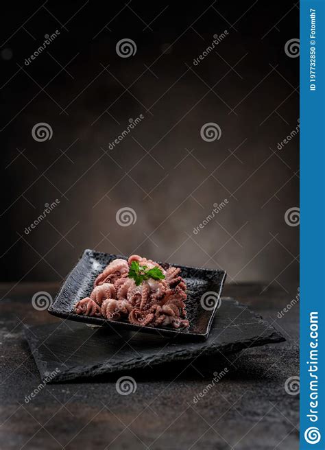 Close Up Photo Of A Black Plate Full With Mini Boiled Octopus Flying