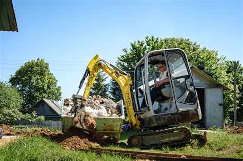민스크 벨라루스 2024년 5월 24일 미니 굴삭기는 토양에 도랑을 파고 있습니다 굴삭기 운전자가 버킷을 제어합니다 크롤러 머신 토공 장비 굴착 건설 현장에서 굴착 작업