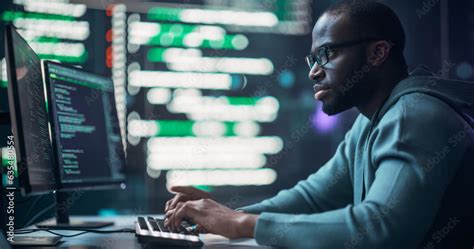 Black Male Programmer Working In Monitoring Room Surrounded By Big