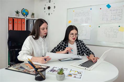 Real Estate Agent And Woman Client Examining Blueprints Before Buying A