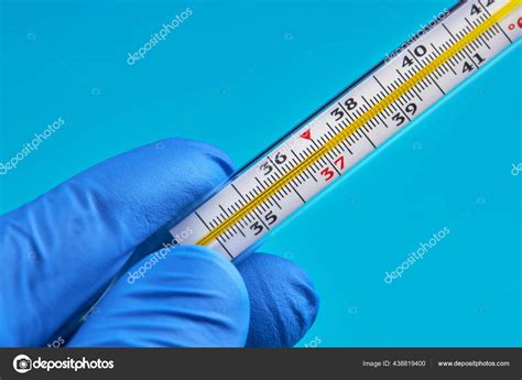 Person In Medical Gloves Holds Mercury Thermometer That Show 37 Temperature Fever Concept