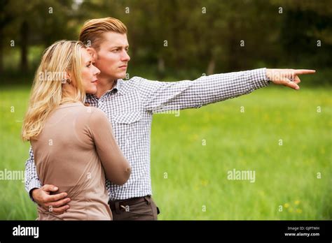 Couple Standing Outdoors And Man Pointing At Something Stock Photo Alamy
