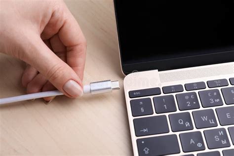 Woman Plugging Usb Cable With Type C Connector Into Laptop Port On Light Wooden Table Closeup