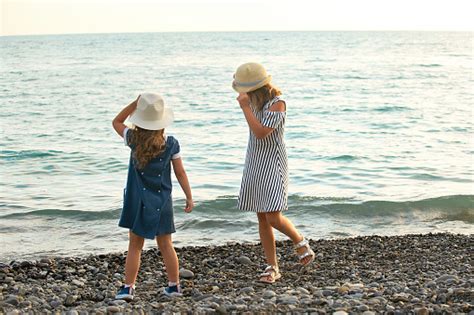 따뜻한 계절에 드레스와 밀짚 모자를 쓰고 해변을 따라 걷는 두 자매 소녀 아이에 대한 스톡 사진 및 기타 이미지 아이 앉음 2명 Istock