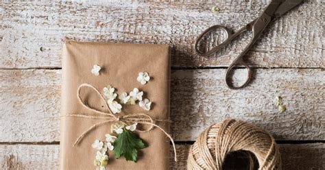 라일락 꽃으로 장식 된 갈색 종이에 싸인 선물 가위와 실 공이 테이블 위에 놓여 있습니다 흰색 나무 배경에 스튜디오를 촬영했습니다 사진 Unsplash의 슬로바키아 이미지