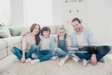 교차 다리 청바지 운동 화 캐주얼 의상을 입고 카메라를 보고 수용 소파 근처 바닥에 앉아 친절 한 세련 된 가족의 초상화 공생 개념 가정 생활에 대한 스톡 사진 및 기타