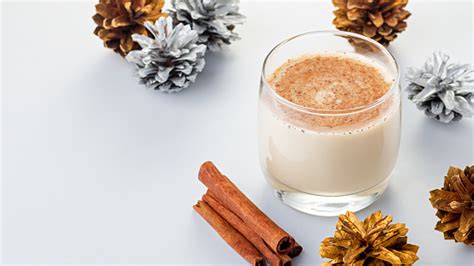 계란 알코올 강판 육두구와 계피 클로즈업 복사 공간 수직 프레임과 전통적인 크리스마스 칵테일 Eggnog 베이지 색 장식과 소나무 콘회색 테이블에 달콤한 전통 음료 0명에