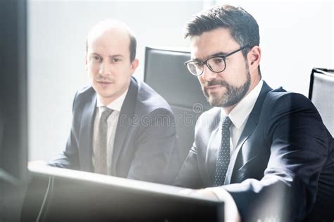Rear View Of Stock Trader Analyzing Data At Multiple Computer Screens
