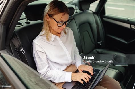 사무실로 가는 길에 자동차 뒷좌석에 앉아 노트북으로 작업하는 안경을 쓴 전문 여성 분석가 45 49세에 대한 스톡 사진 및 기타 이미지 45 49세 교통수단 낮