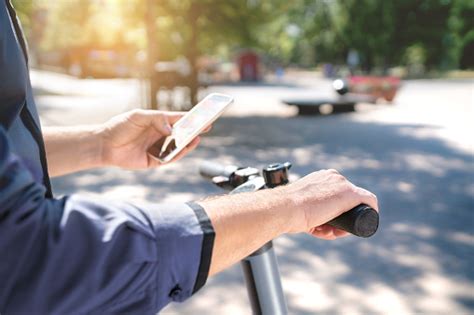 도시에서 전기 스쿠터입니다 전자 킥 차량을 임대하는 스마트 폰을 사용하는 남자 시내에서 에코 전송을 사용하여 휴대 전화를 가진 밀레니엄 남자 트래픽에 있는 비즈니스 사람