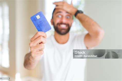 신용 카드를 들고 잘 생긴 히스패닉 남자는 머리에 손으로 스트레스 수치와 깜짝 얼굴 분노와 좌절에 충격 실수에 대한 두려움과 화가 계산대에 대한 스톡 사진 및 기타 이미지