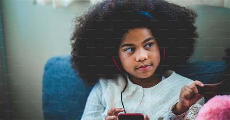 빨간 하트 모양의 쿠션 베개를 들고 집에서 엄마와 놀고 있는 행복한 작은 혼합 아피칸 소년 귀여운 소년은 행복을 숨길 수 없어 엄마와 함께 있는 동안 미소를 짓고