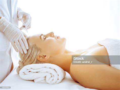 미용사 의사는 병원에서 주사기로 여성 금발 얼굴에 미용 시술을 하고 있다 미용 의학 및 수술 미용 주사 개념 25 29세에 대한 스톡 사진 및 기타 이미지 Istock