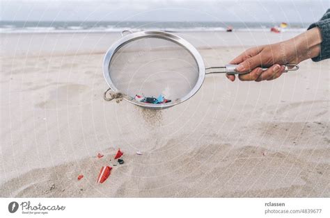 Young Woman Cleaning Microplastics From Sand On The Beach