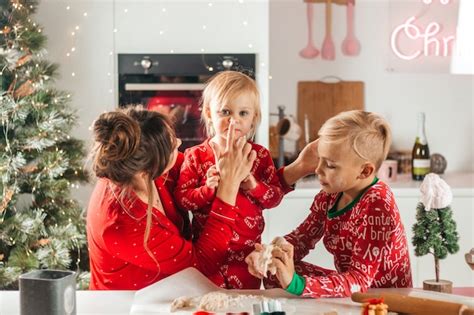 Feliz navidad madre e hijos hacen galletas de navidad ensuciándose con harina en rojo Foto