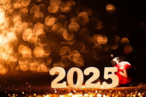 2025년 다크 뉴 이어는 황금빛 갈색의 반짝이는 보케 배경에 흰색 하트가 그려진 빨간색 크리스마스 싸구려와 함께 밝은 숫자가 표시됩니다 0명에 대한 스톡 사진 및 기타