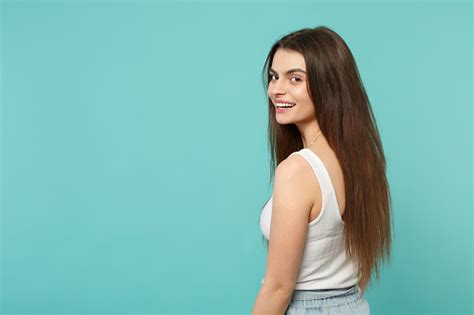 밝은 캐주얼에 아름 다운 젊은 여자의 뒷면 뒷 전망 스튜디오에서 파란색 청록색 벽 배경에 고립 된 찾고 사람들은 진심으로 감정 라이프 스타일 개념입니다 복사 공간을 모의
