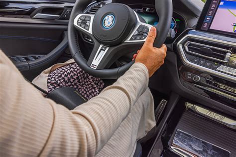 Bmw Ix3m 전기차의 스티어링 휠에 손을 얹은 여성의 손을 클로즈업한 모습 Bmw에 대한 스톡 사진 및 기타 이미지