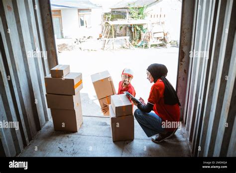 Male Workers In Red Lifting Boxes With Female Workers Checking Stock