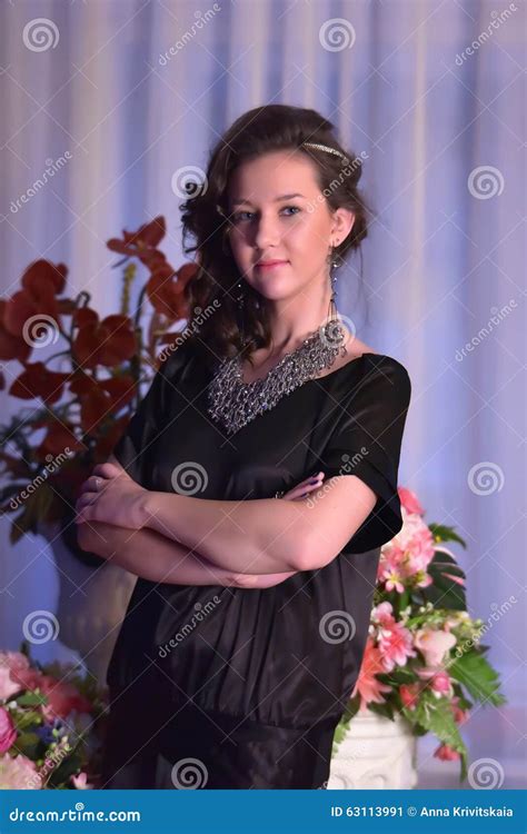 Девушка в черном платье рядом с вазой с цветками Стоковое Изображение