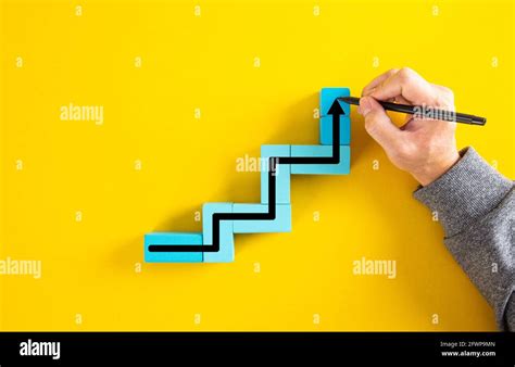 Male Hand Drawing An Upward Pointing Arrow On Top Of Growing Graph Made Of Wooden Blocks Over