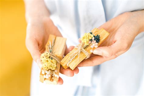 노란 벽에 마른 꽃과 향기로운 허브로 장식된 팔로 산토 스틱을 들고 있는 여자 훈증 의식 과정 명상을 위해 팔로 산토 굽기 백단에 대한 스톡 사진 및 기타 이미지 Istock