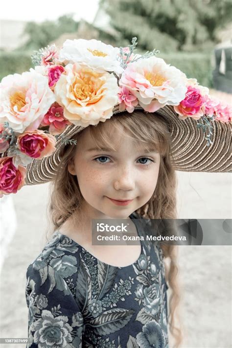 꽃이 있는 밀짚 모자를 쓴 사랑스러운 파란 눈십대 소녀의 큰 초상화 긴 푹신한 머리를 가진 매력적인 소녀는 미소와 함께 카메라를 본다 모자 모자류에 대한 스톡 사진 및 기타