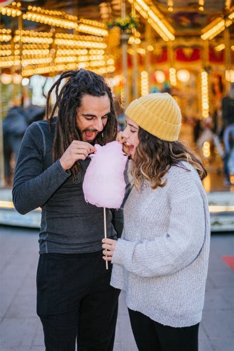Young Couple Having Fun And Eating Cotton Candy At A Christmas Fair