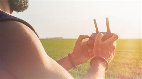 수염 남성 모델 하늘에서 장치를 비행 하는 공중 드 론 원격 제어를 사용 합니다 일몰 녹색 쌀 밭을 통해 비행 공중 무인 항공기 와이드 배너 긴 형식입니다 T 셔츠에 대한
