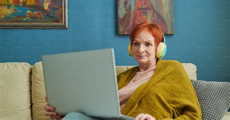 무선 헤드셋을 착용한 노인 여성이 소파에 앉아 무릎을 꿇고 집에서 여가 시간에 온라인으로 영화를 보고 있다 사진 Unsplash의 러시아 이미지