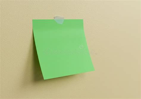 A Green Sticky Note Secured To A Beige Wall With A Small Piece Of Translucent Tape At Stock