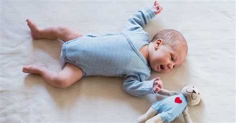 침대에 누워 있는 파란색 줄무늬 옷을 입은 귀여운 신생아 그 옆에 빨간 하트가 있는 테디베어 장난감 사진 Unsplash의 아기 이미지