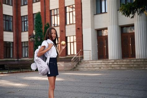 Premium Photo Fresh Apple In Hand School Girl In Uniform Is Outdoors Near The Building