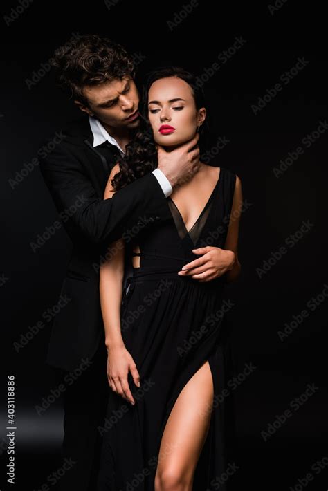 Passionate Man Choking Sexy And Submissive Woman In Dress On Black