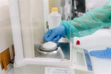 Hands Of Female Scientist Measuring Powder Medicine On Scale In Laboratory Stock Photo