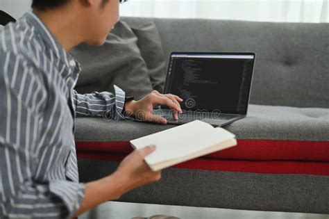 Male Programmer Sitting On Floor In Living Room Working On Laptop Computer With Programming