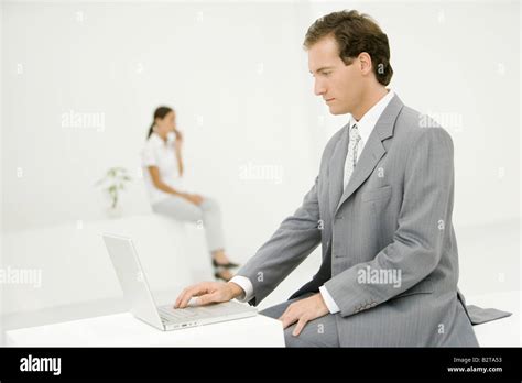 Professional Man Using Laptop Computer Female Colleague In Background Stock Photo Alamy