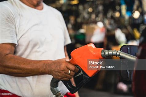 연료 인젝터를 들고 있는 작업자가 자동차에 연료를 보급하고 있습니다 50 54세에 대한 스톡 사진 및 기타 이미지 50 54