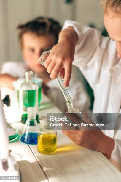 실험실에서 화학 실험을하고 흰색 유니폼을 입은 심각한 어린 소년과 소녀 학교 개념으로 돌아갑니다 젊은 과학자 자연과학 유치원 및