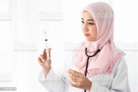 청진기를 입은 아름다운 젊은 무슬림 여성 의사의 초상화가 서서 고립 된 흰색 배경에 환자를 주입 할 주사기를 들고 있습니다 20 29세에 대한 스톡 사진 및 기타 이미지