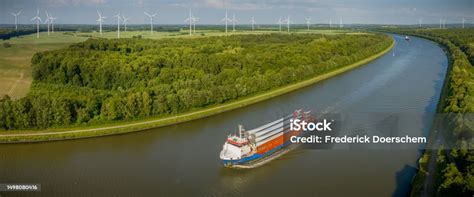 풍력 터빈 블레이드를 실은 화물선이 풍력 발전 단지를 배경으로 킬 운하를 항해하고 있습니다 화물선의 풍력 터빈용 블레이드 운송