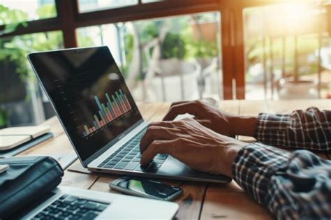 Hands Typing On A Laptop Keyboard Displaying An Analytical Graph On The Screen In A Sunlit