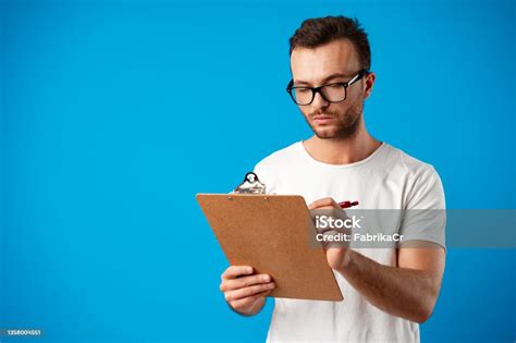 파란 배경에 대한 클립 보드에 메모를 만드는 젊은 남자의 초상화 클립 보드에 대한 스톡 사진 및 기타 이미지 클립 보드 남자 쓰기 Istock