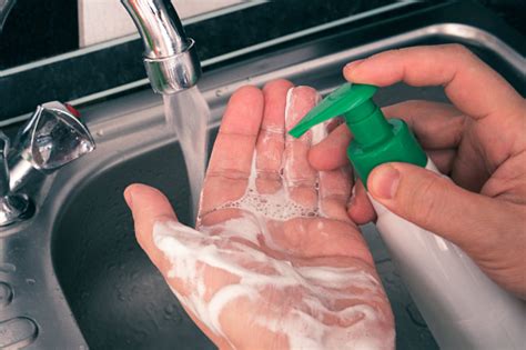 부엌 싱크대에서 손을 씻는 남자의 클로즈업 한 남자가 금속 싱크대 의 배경에 비누로 손을 바헤치고 있습니다 병에 살균 항균 비누 가정 주방에 대한 스톡 사진 및 기타 이미지