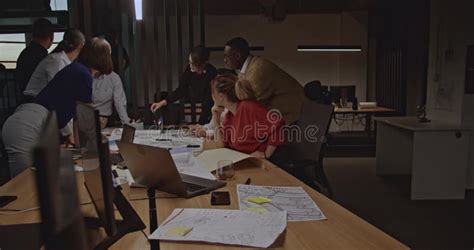 Diverse Business Team Collaborates On Project In Modern Office Reviewing Blueprints And Data On