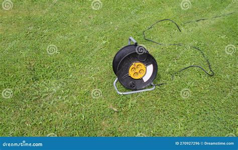 Black Electric Power Cord And Plug Socket Outlet On Green Grass Field