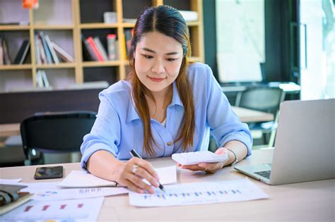 사무실의 책상에 앉아 있는 비즈니스 아시아 여성 계산기를 사용하여 작업합니다 사업 개념 분석 및 계획 25 29세에 대한 스톡