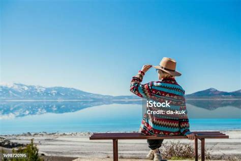 Woman Sitting Near Beautiful Blue Lake With White Sand Beach And