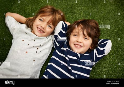 Hanging Out With My Sibling Brother And Sister Relaxing On The Grass In The Backyard Stock